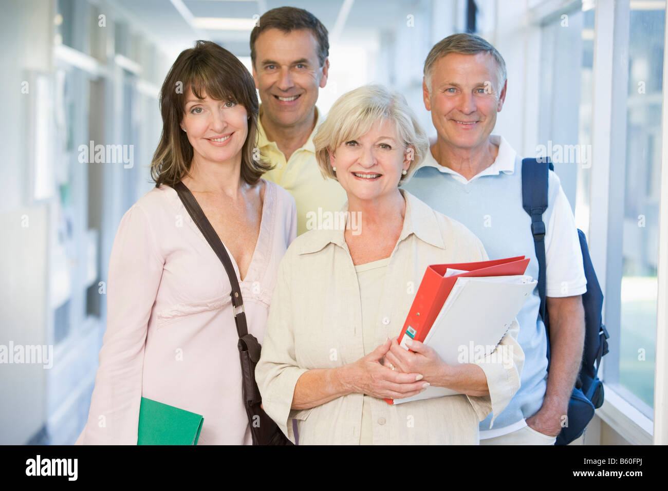 Four people standing in corridor with books (high key Stock Photo - Alamy