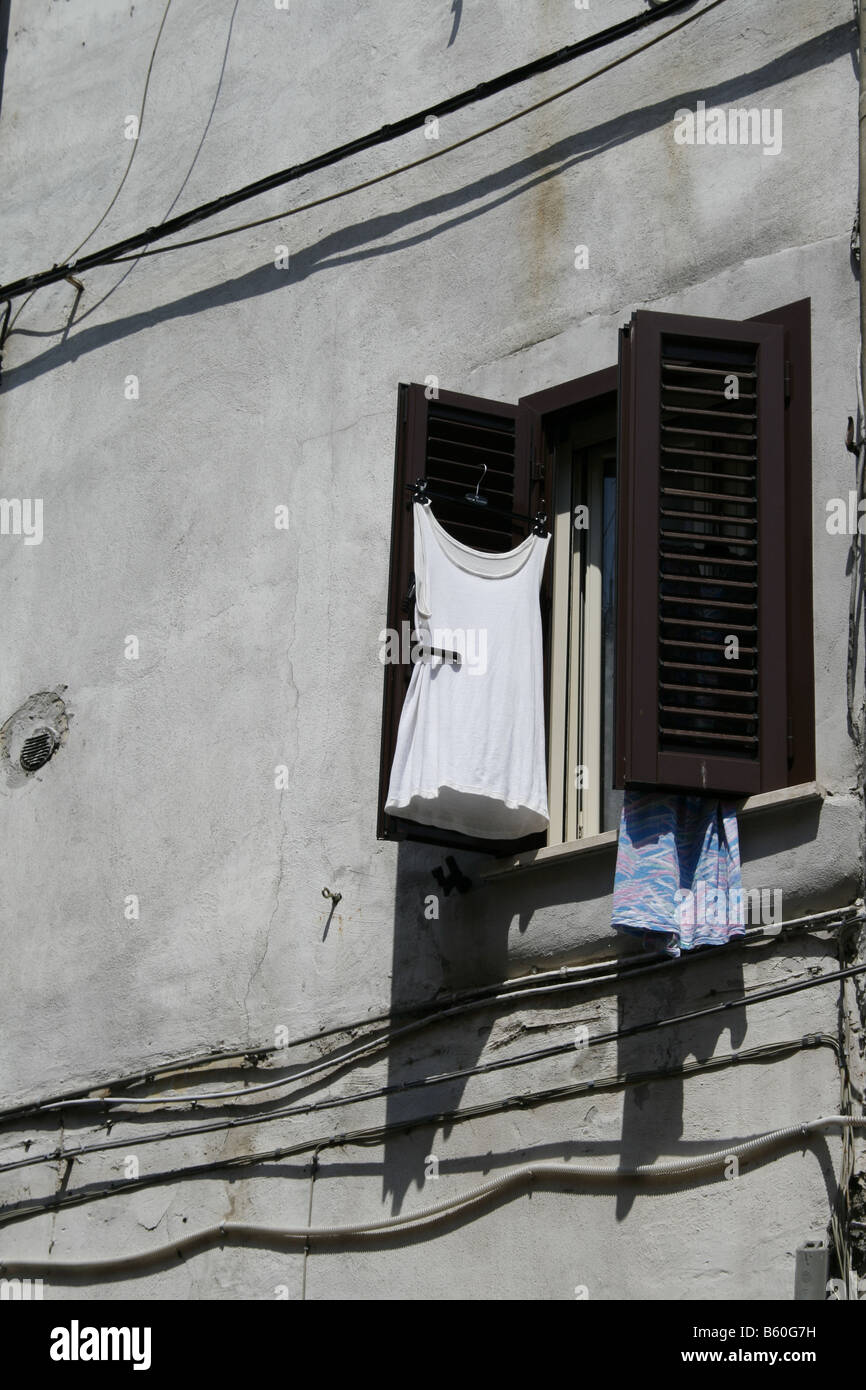 one white vest on washing line outdoors in apartment block in sun in ...