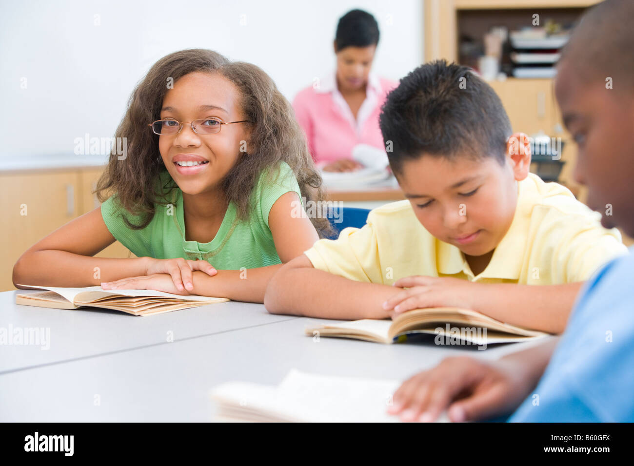 Students in class reading with teacher in background (selective focus ...