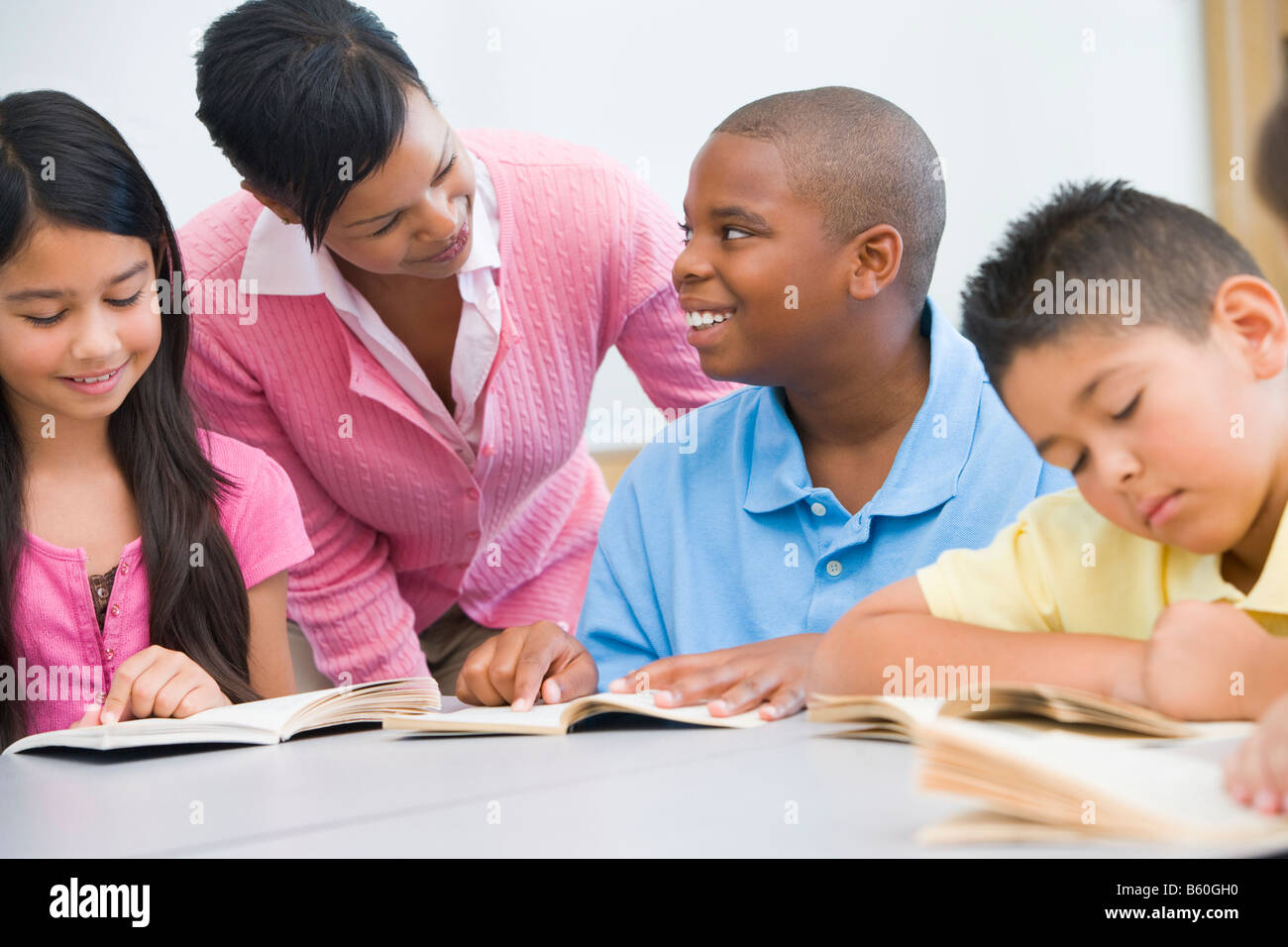 Students in class reading with teacher helping (selective focus Stock ...