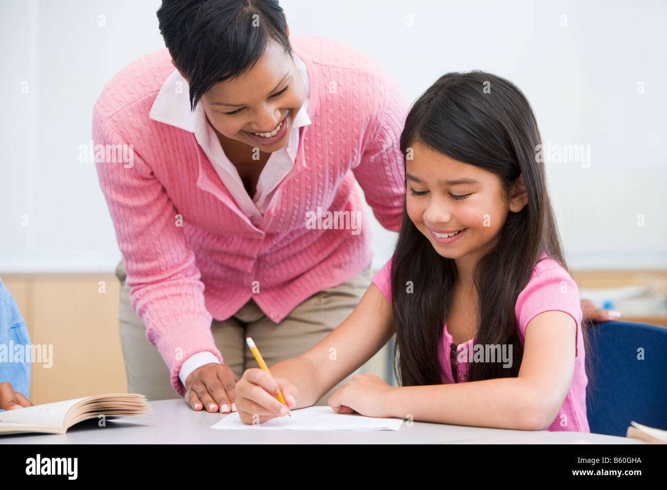 Student in class writing with teacher Stock Photo - Alamy