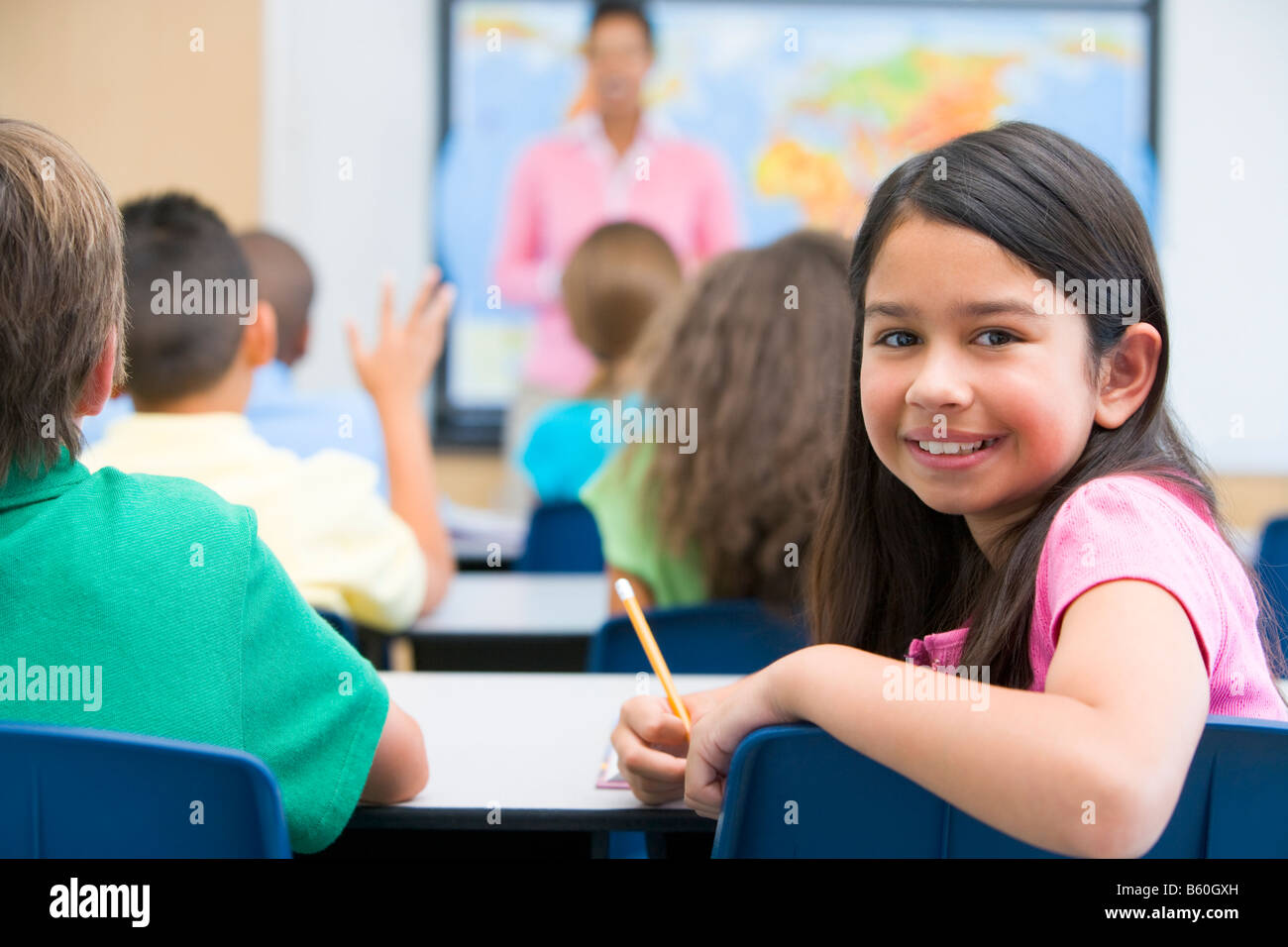 Student in class looking at camera with teacher in background ...