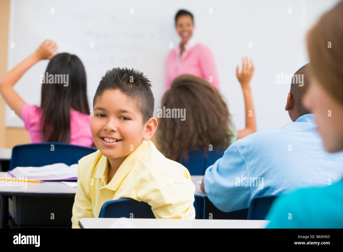 Student in class looking at camera with teacher in background ...