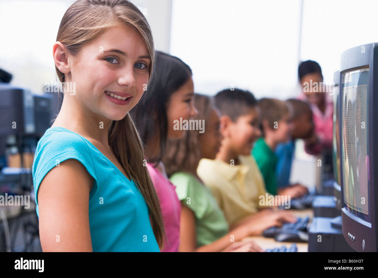 Six children at computer terminals with teacher in background (depth of ...