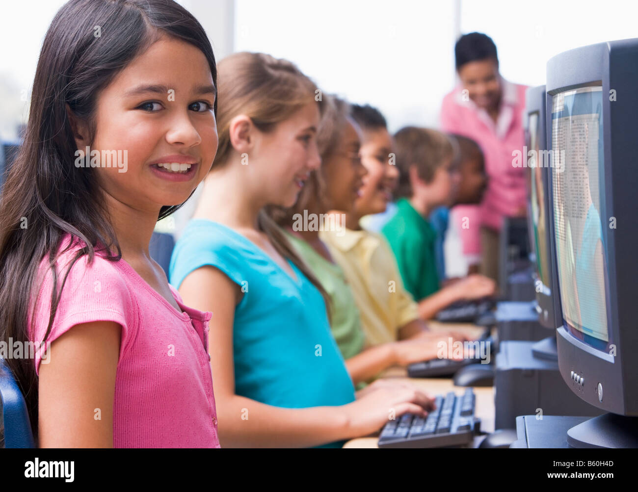 Six children at computer terminals with teacher in background (depth of ...