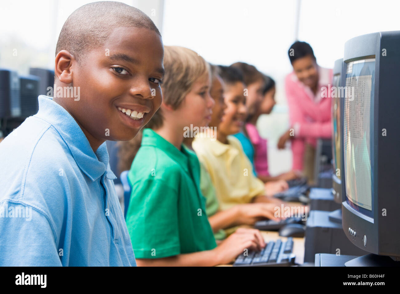 Six children at computer terminals with teacher in background (depth of ...