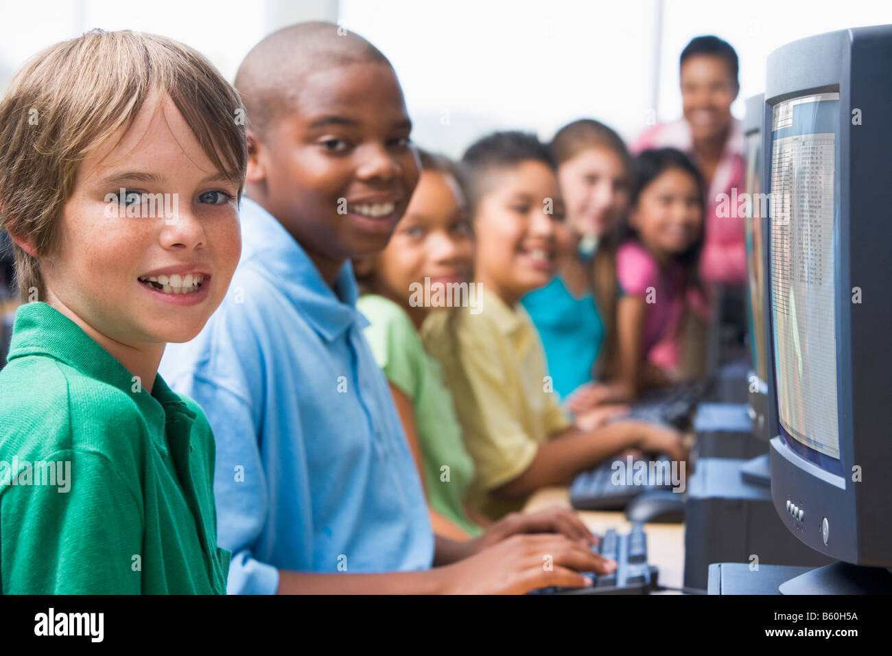 Six children at computer terminals with teacher in background (depth of ...