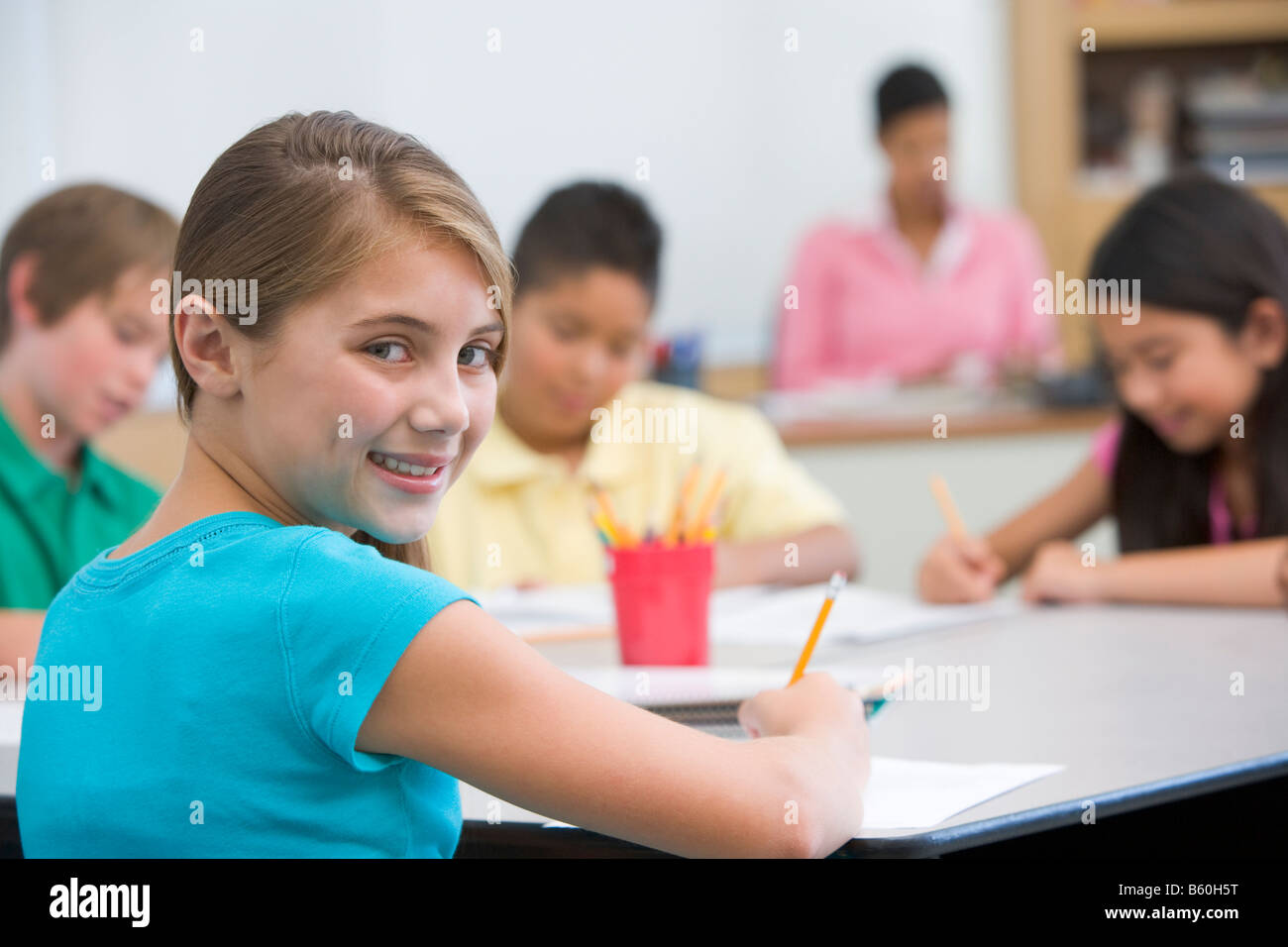 Students in class taking notes with teacher in background (selective ...