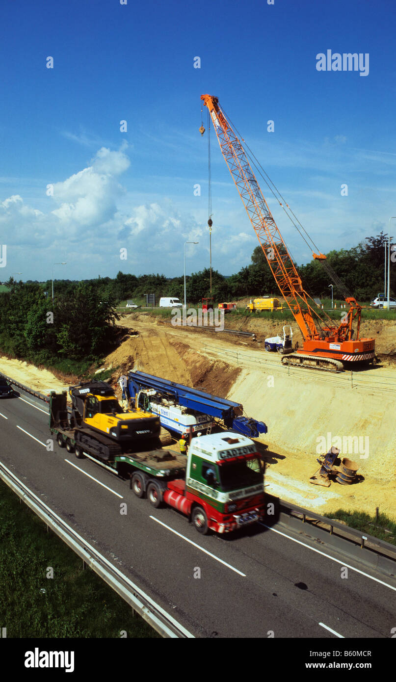 low loader lorry carrying mechanical digger through upgrade roadworks ...