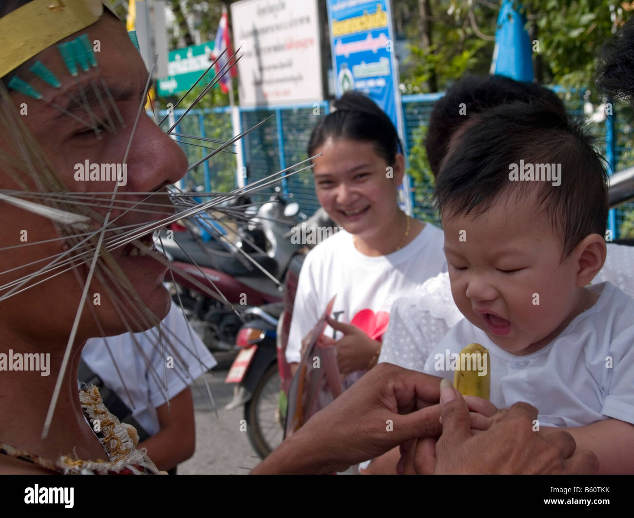 man in a trance with needles in his face blessing a child at the ...