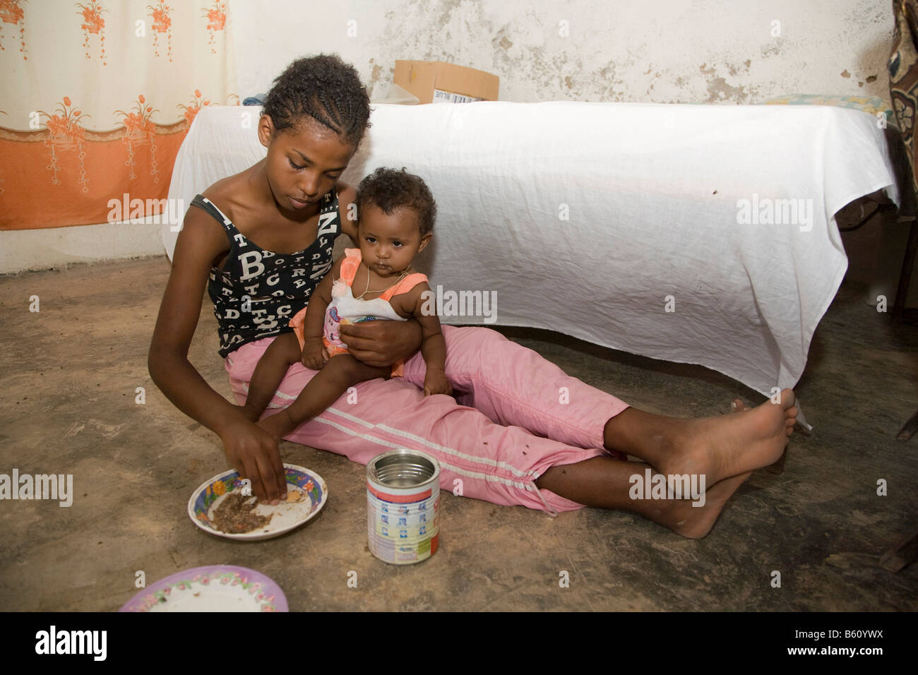 Young girl, 10-15 years old, feeding a baby with porridge, Eritrea ...