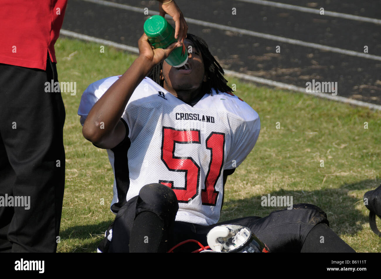 High school football player takes a break and gets a drink of water ...