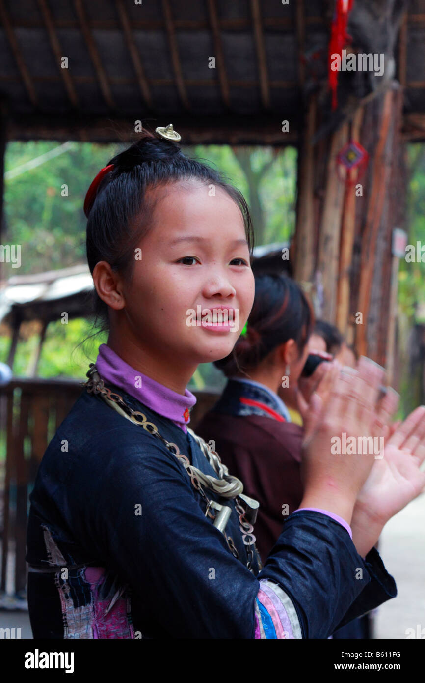 Smiling Miao girl clapping hands to greet tourists to their tribe in ...