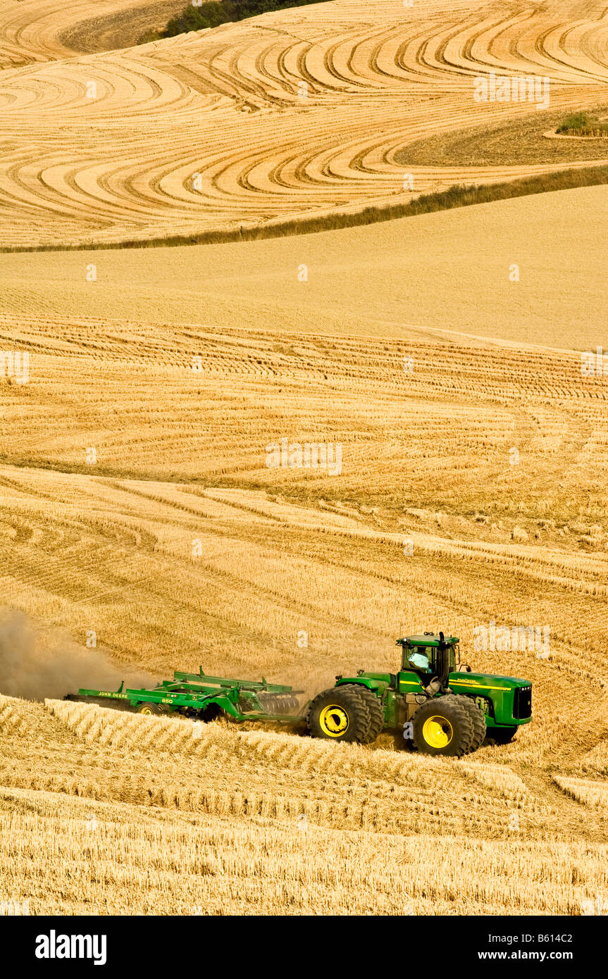 A tractor pulls a disk through the stubble of recently harvested grain ...