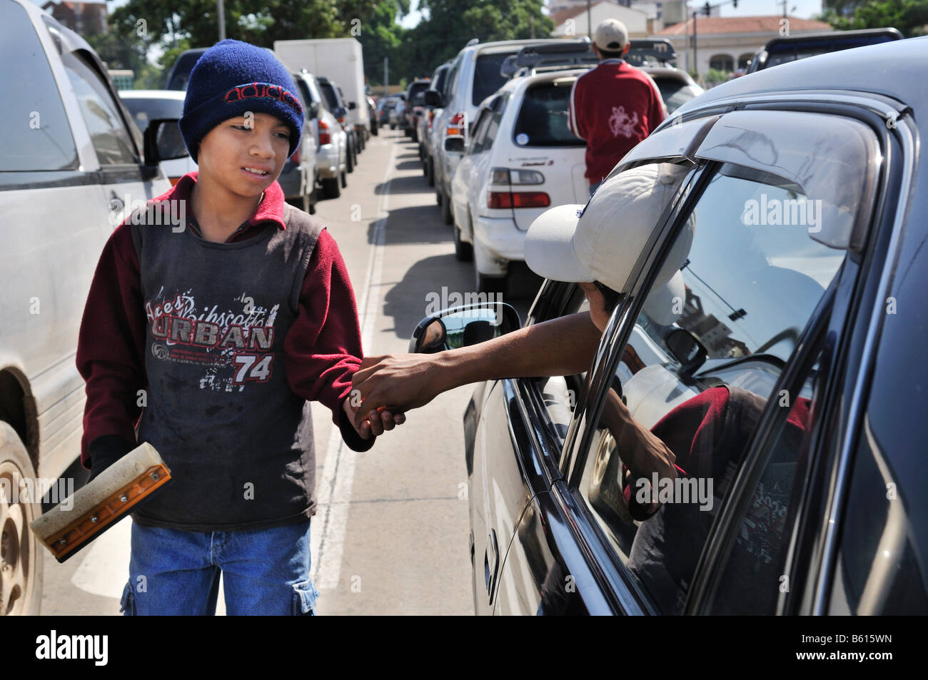 Child labour, ten-year old boy receiving payment for cleaning car ...