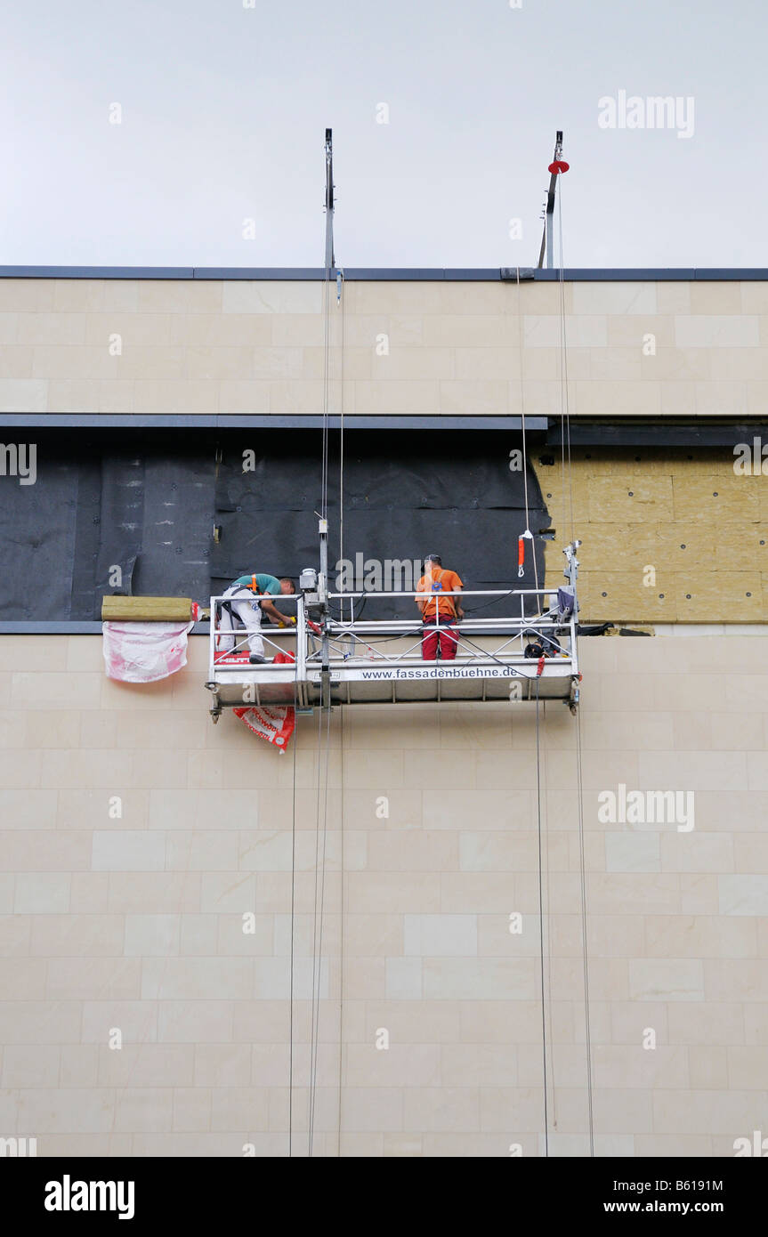 Building workers on a work platform applying insulating material ...