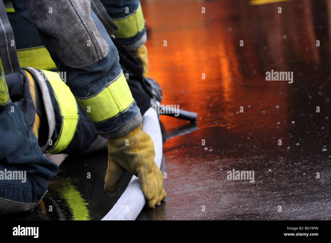 The hose laying beside fire fighters at a scene where the flames are ...