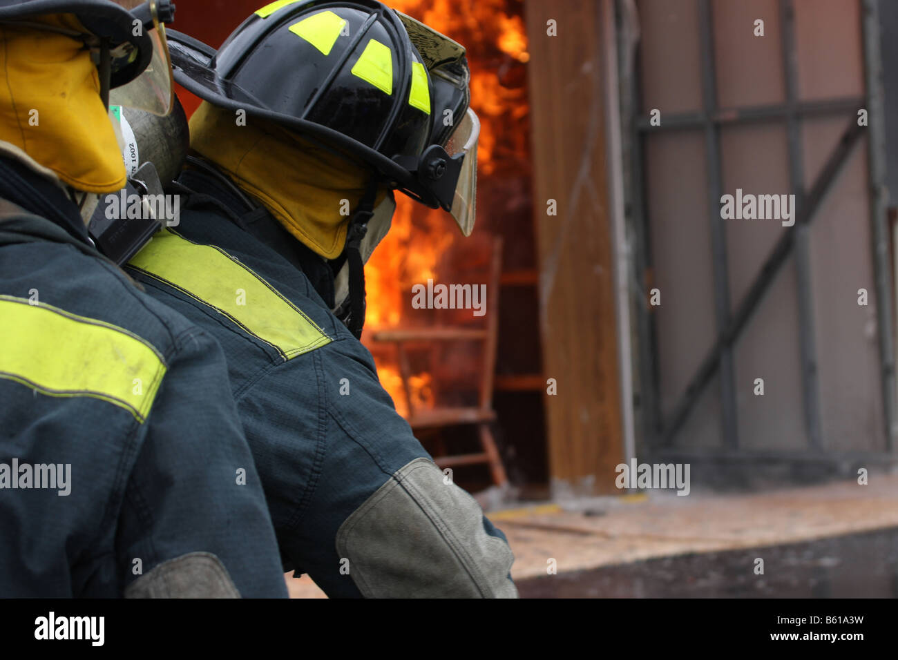 Two fire fighters surrounded by smoke while putting out a fire with a ...