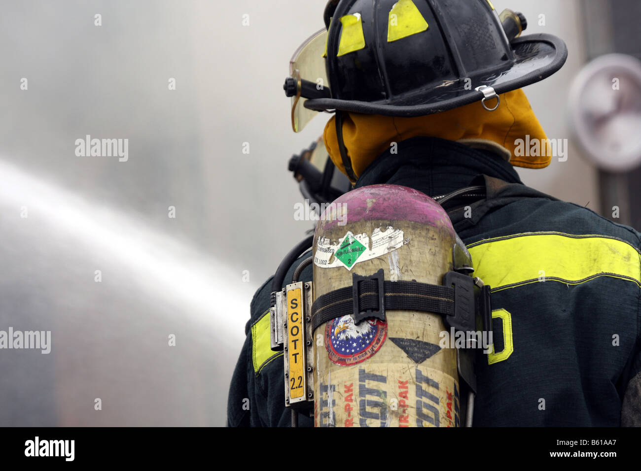 Two fire fighters surrounded by smoke while putting out a fire with a ...