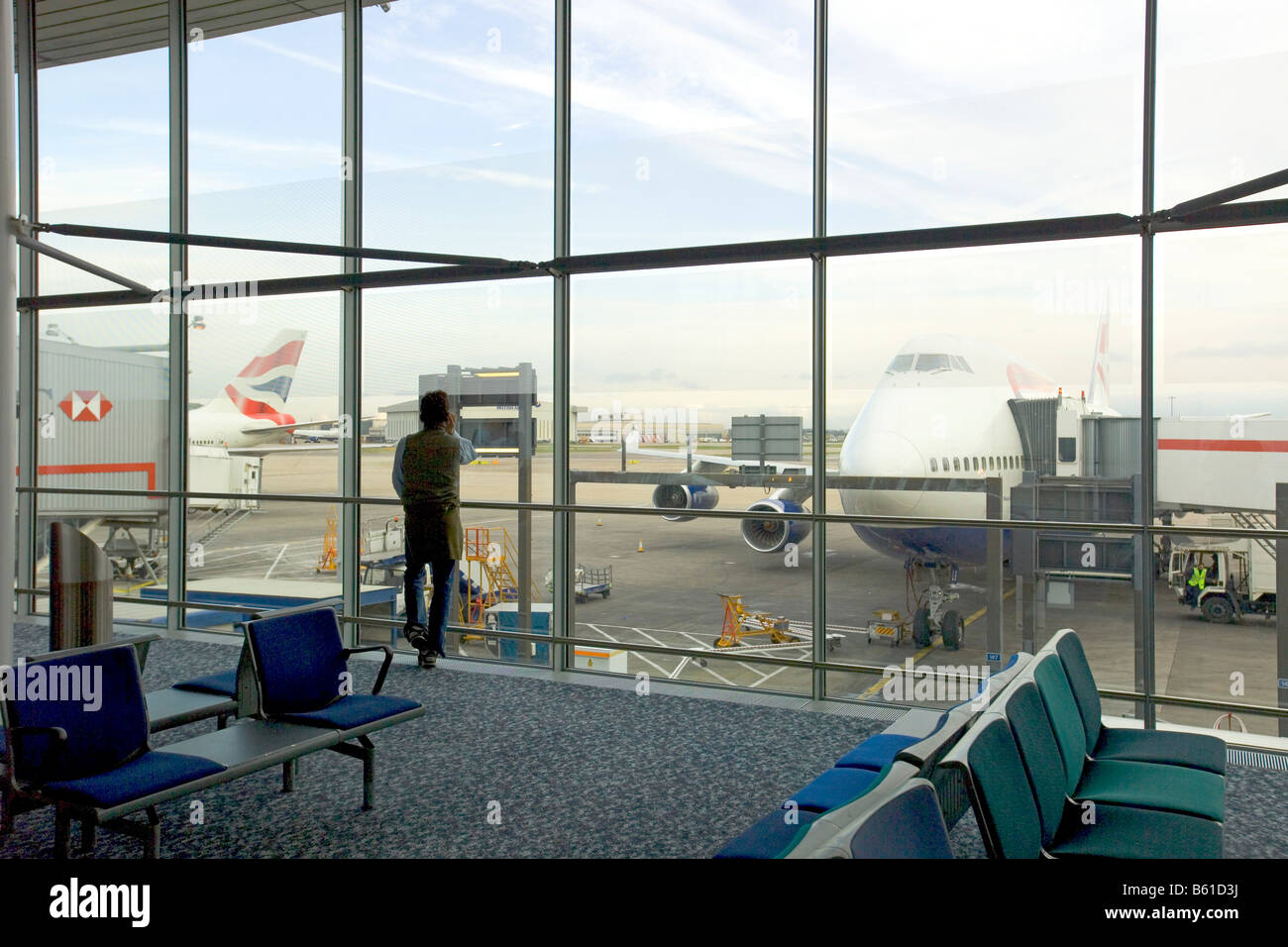 A departure lounge with a lone passenger talking on his mobile phone ...