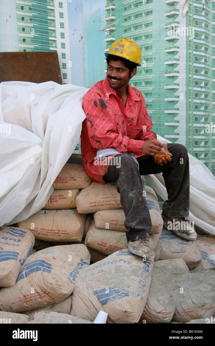 construction worker wearing hard hat sitting on cement bags on ...