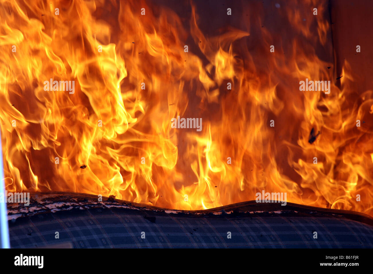 A couch on fire with debris in the air Stock Photo - Alamy