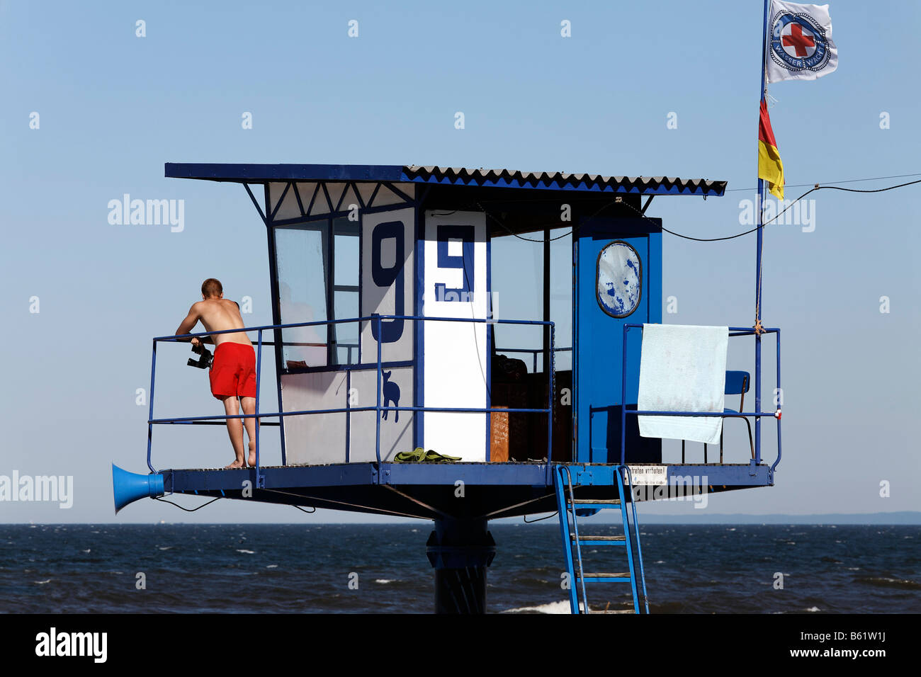 Beach watch tower, life-saving lookout, young man observing the beach ...