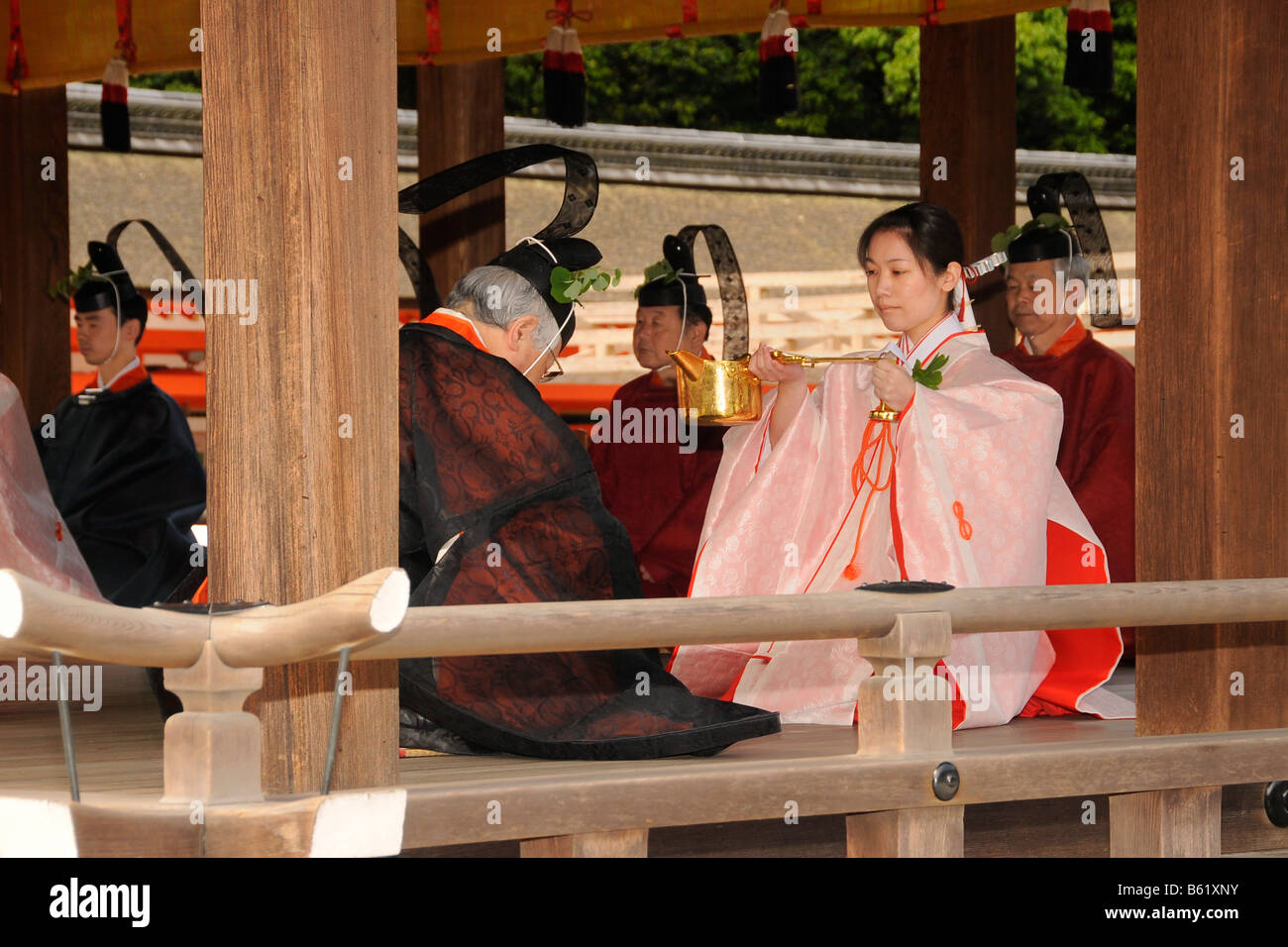 A temple servant dressed in a kimono assists a priest during his ...