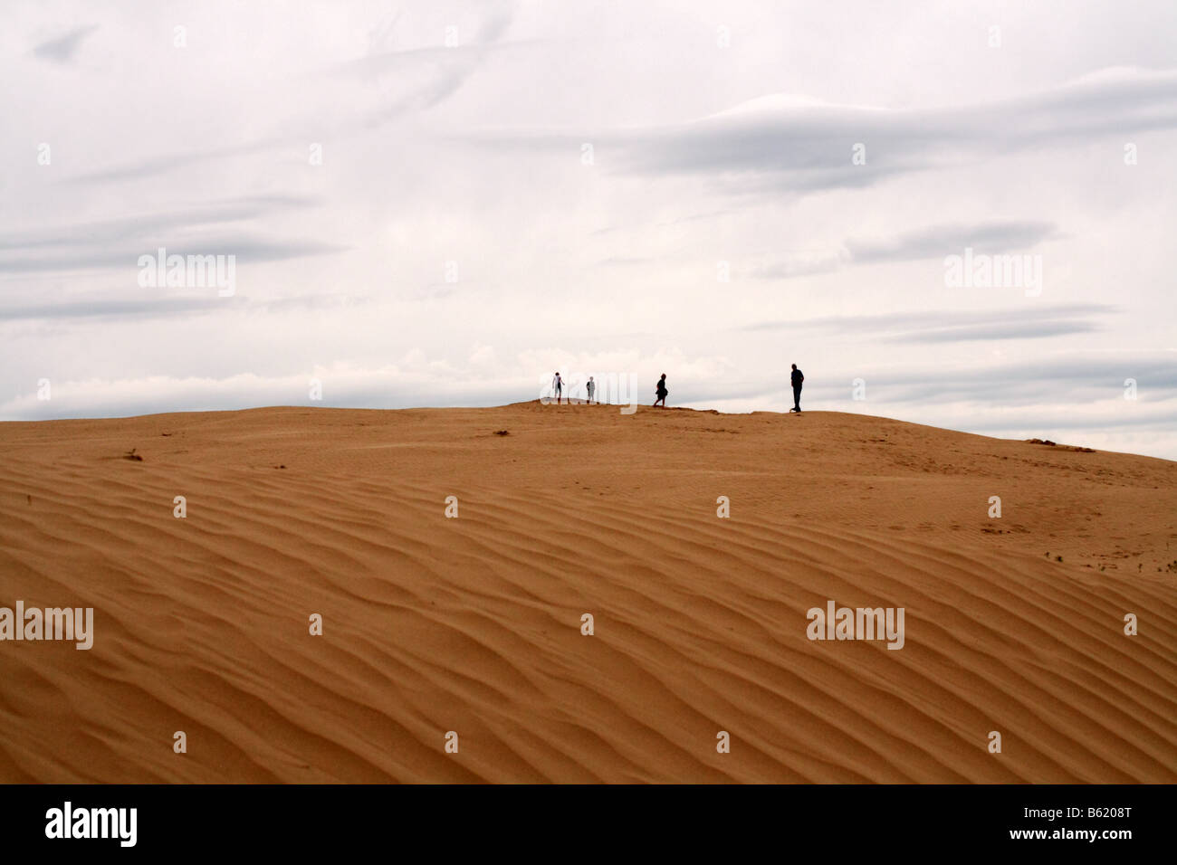 Family playing under dramatic desert sky in Great Sand Hills in ...