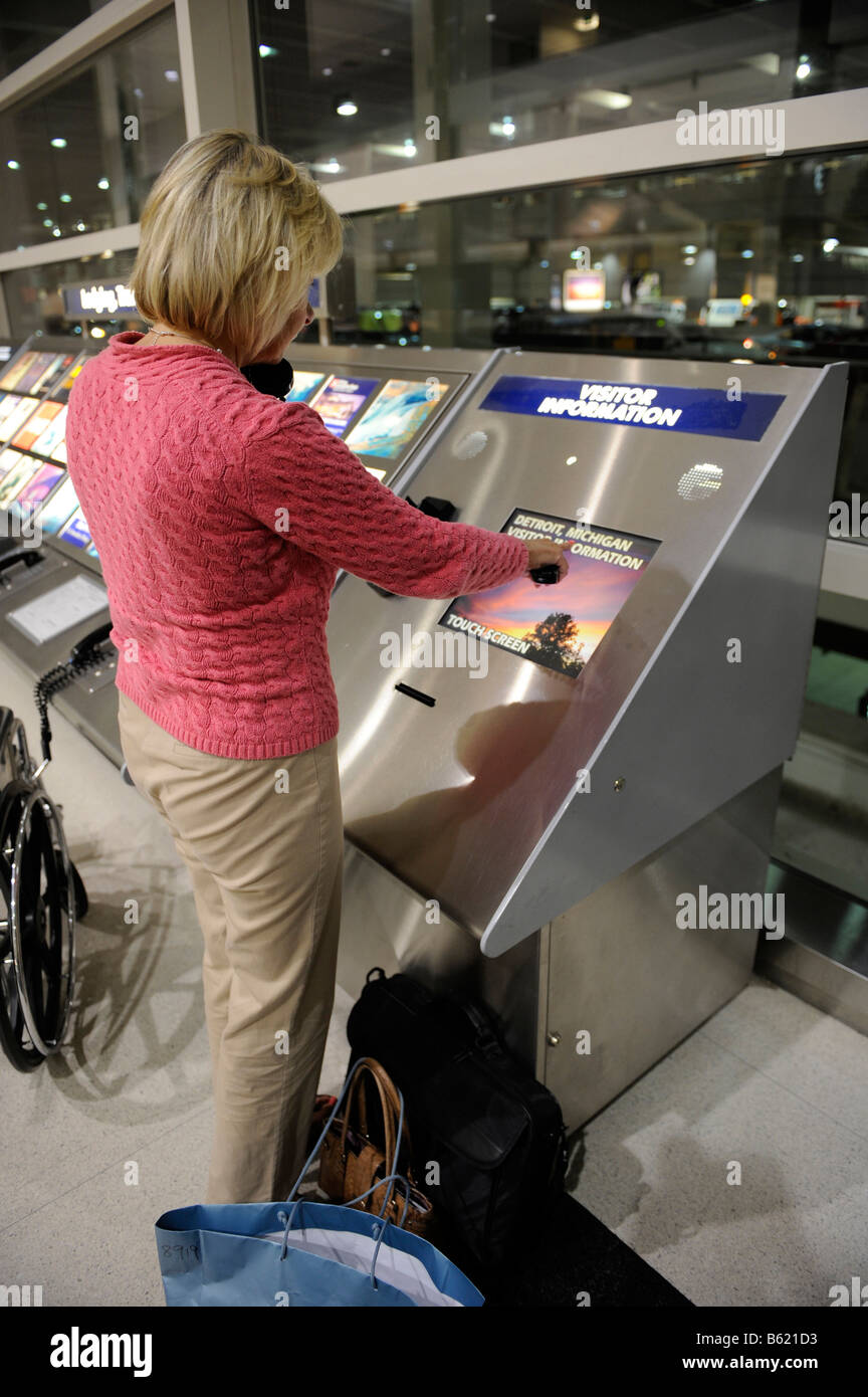 Female visitor seeks help at visitor information display at airport ...