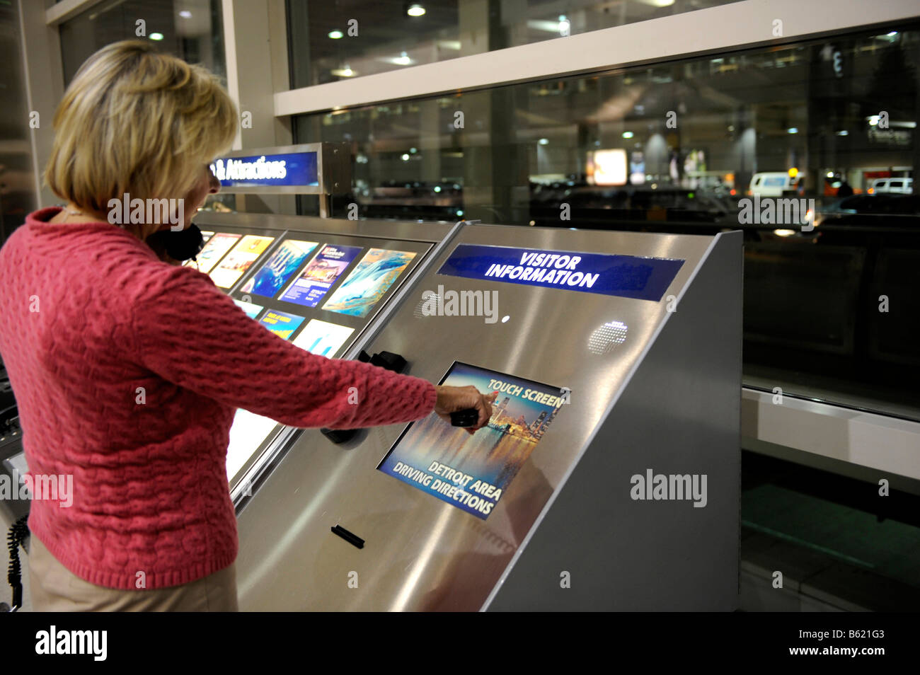 Female visitor seeks help at visitor information display at airport ...