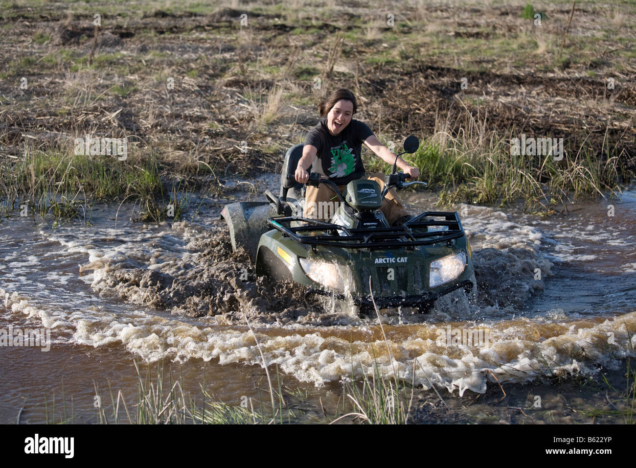 USA Montana Kalispell Young woman rides four wheeler ATV in muddy ...