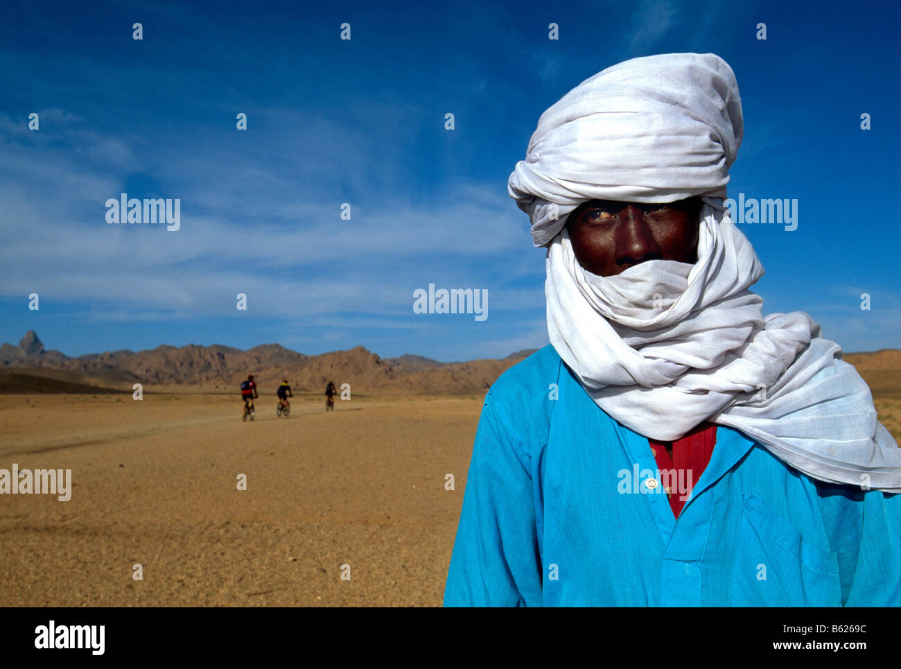 Touareg man in front of mountainbikers, Ahaggar National Park, Ahaggar ...