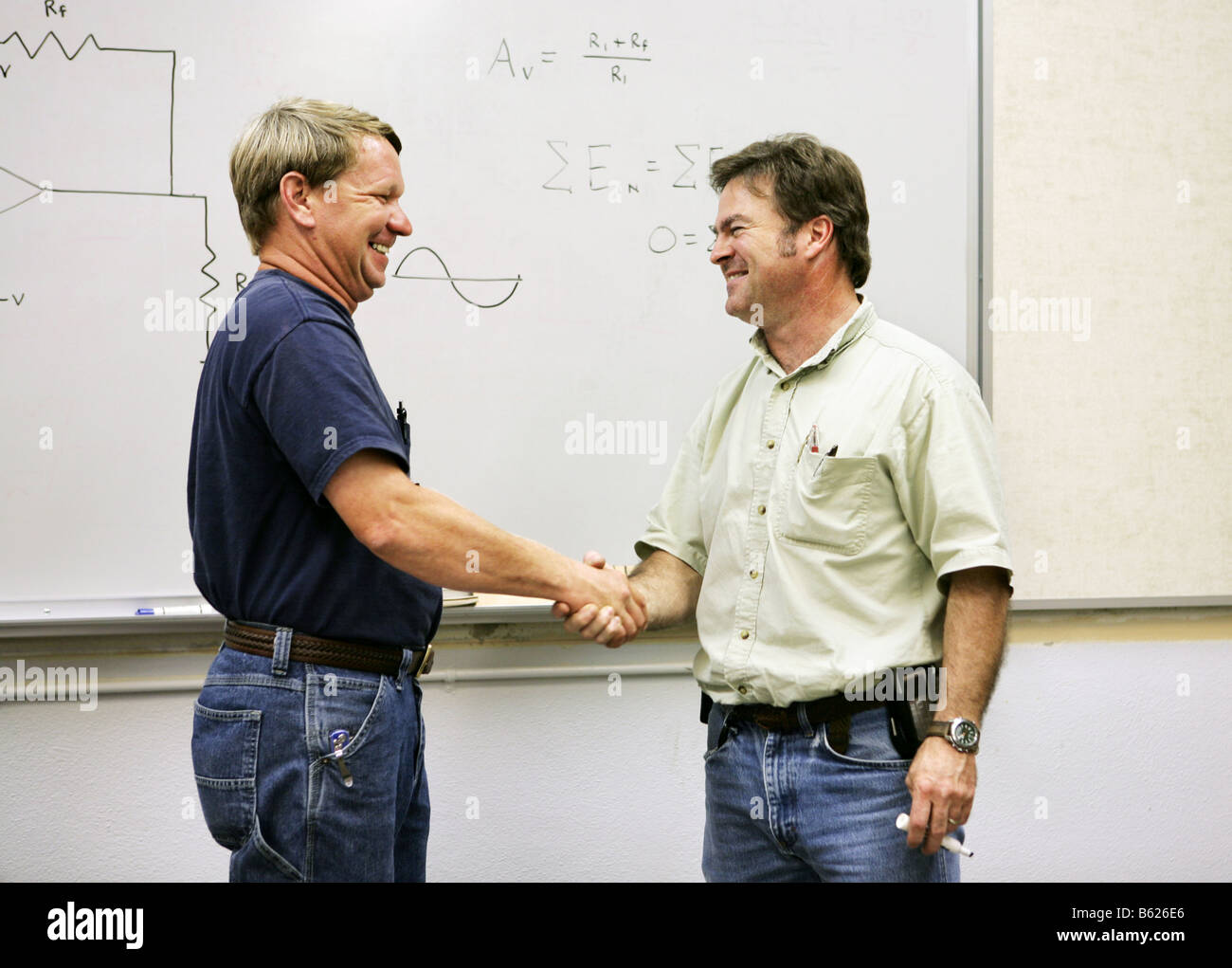 An adult student shaking hands with his teacher in front of the white ...