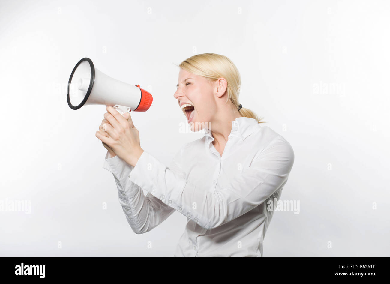 Young blonde woman shouting into a megaphone Stock Photo - Alamy