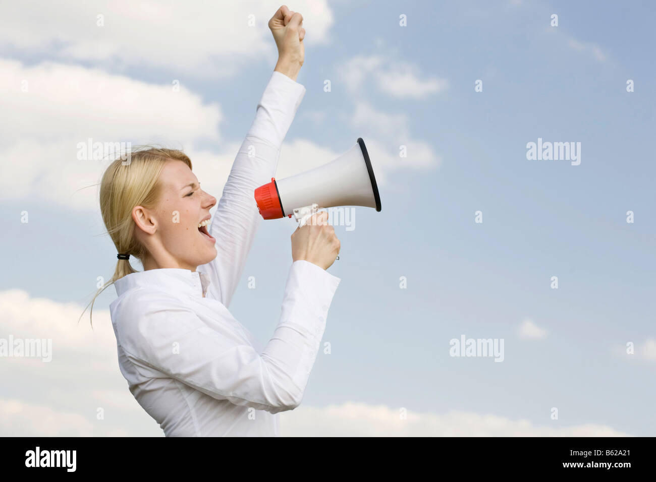 Young blonde woman shouting into a megaphone Stock Photo - Alamy