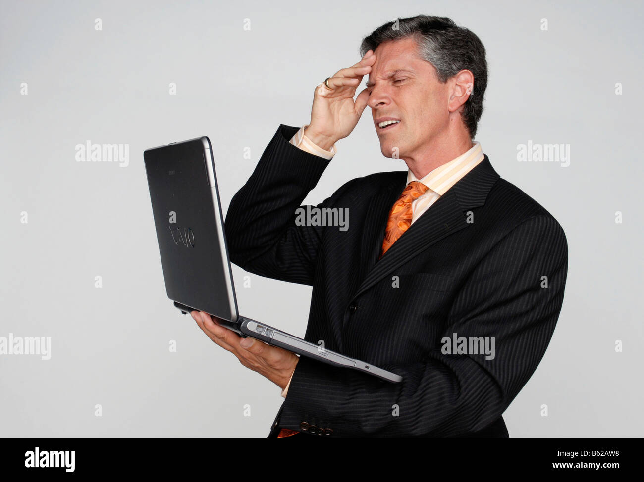 Man slapping his forehead, holding a laptop in the other hand Stock ...