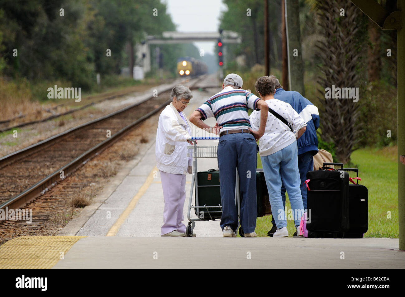Railroad passengers with luggage trolley and bagage on railroad station ...