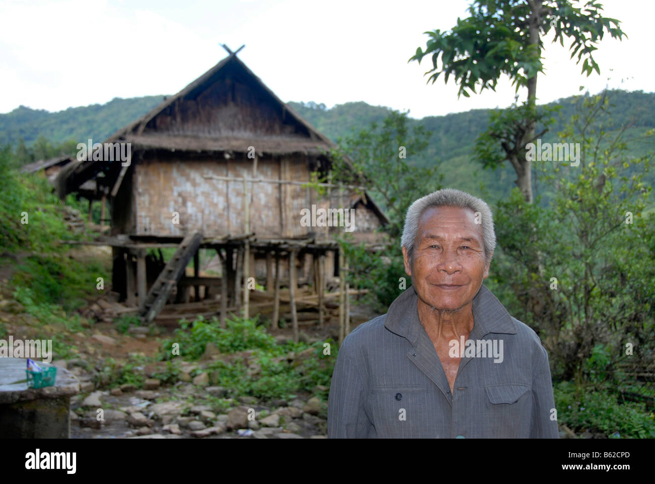 Portrait of a man of the Lao Seng tribe in front of a hut on stilts in the village of Ban Tang ...