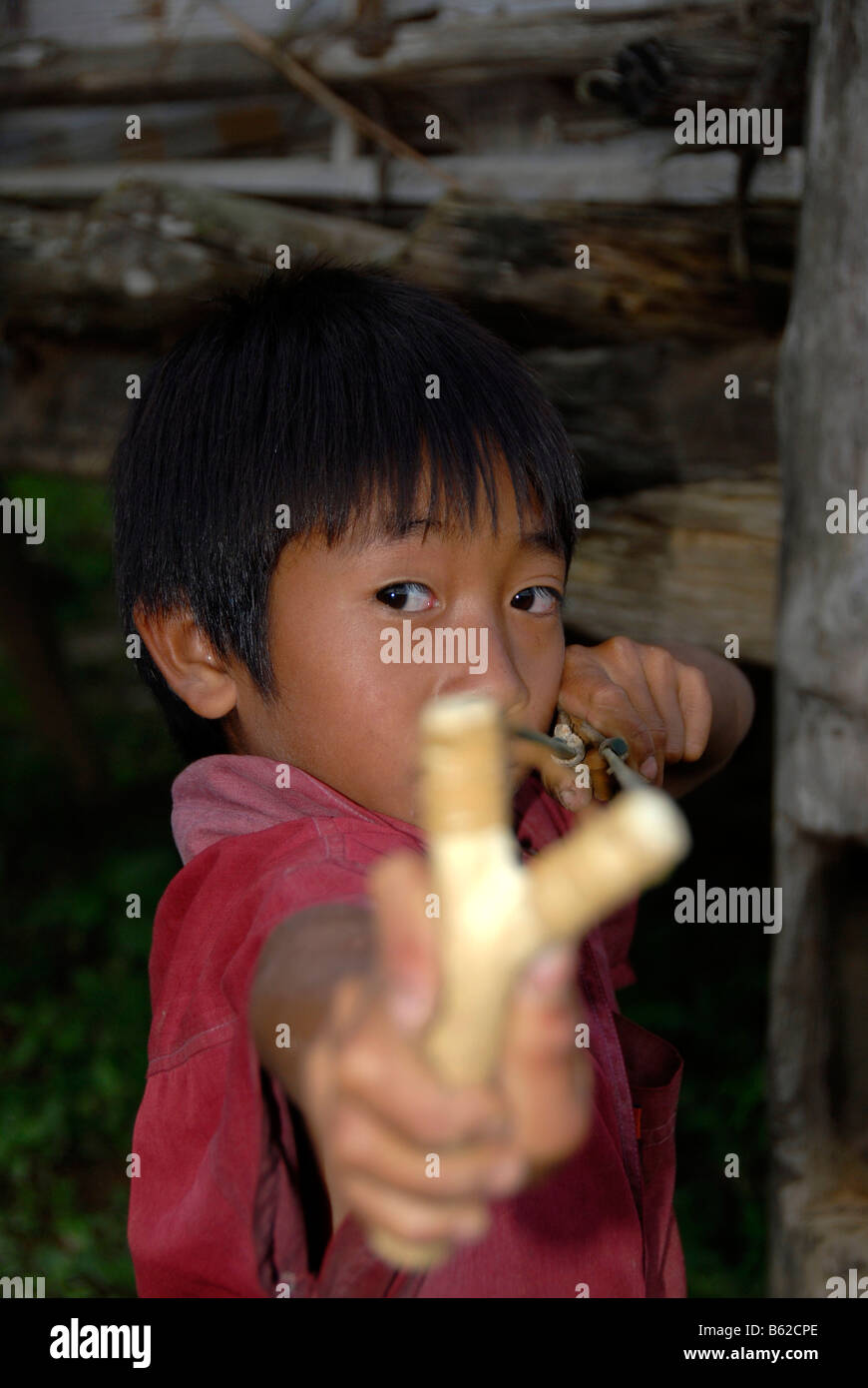 Young boy of the Lao Seng tribe aiming at the photographer with his ...