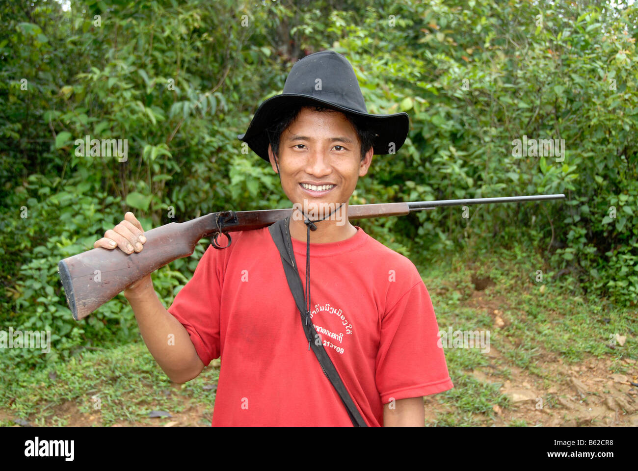 Portrait of a man of the Akha A-koo tribe with a gun casually slung ...