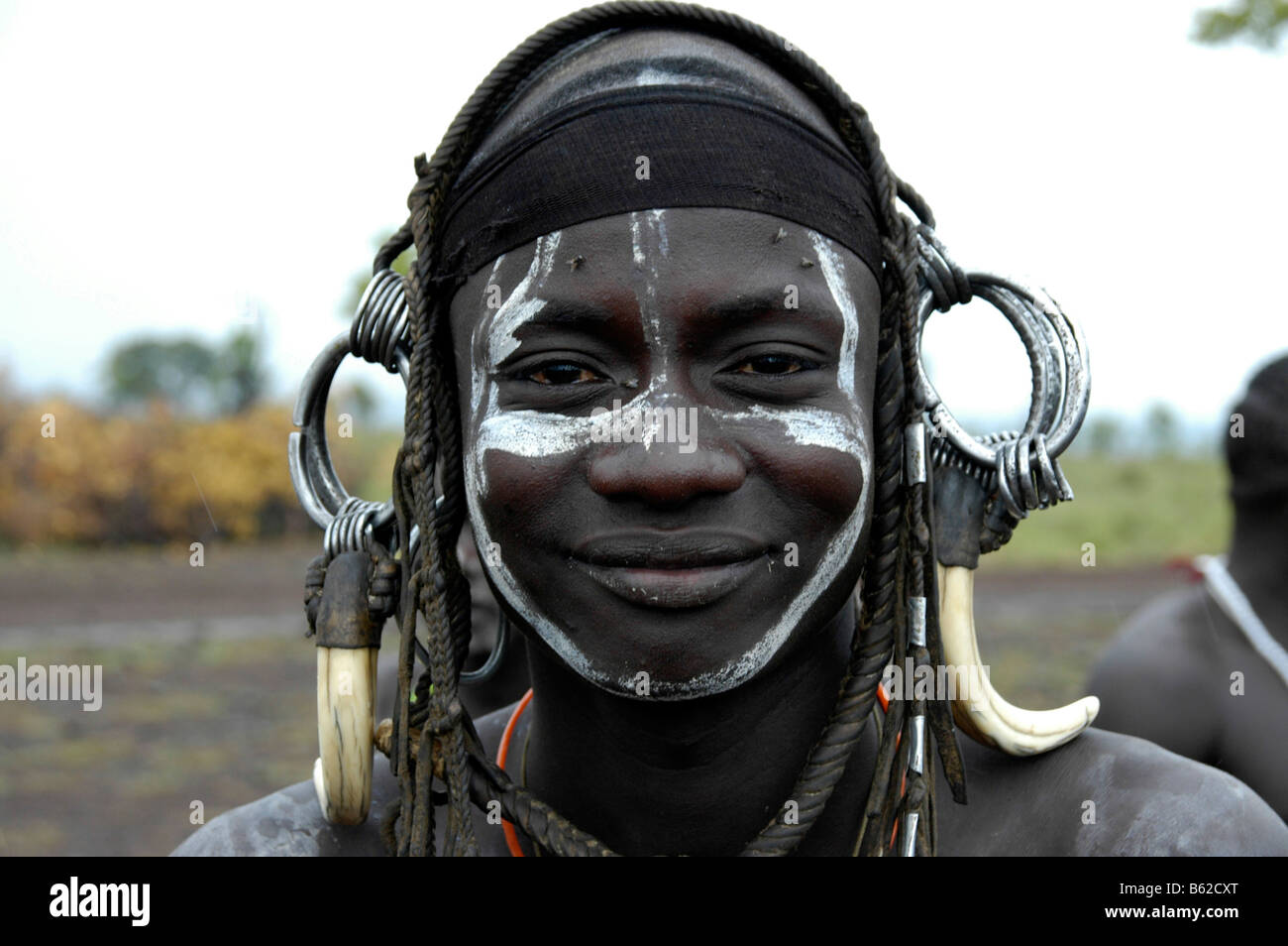 Portrait of a smiling young man from the Mursi tribe, wild, heavy ...
