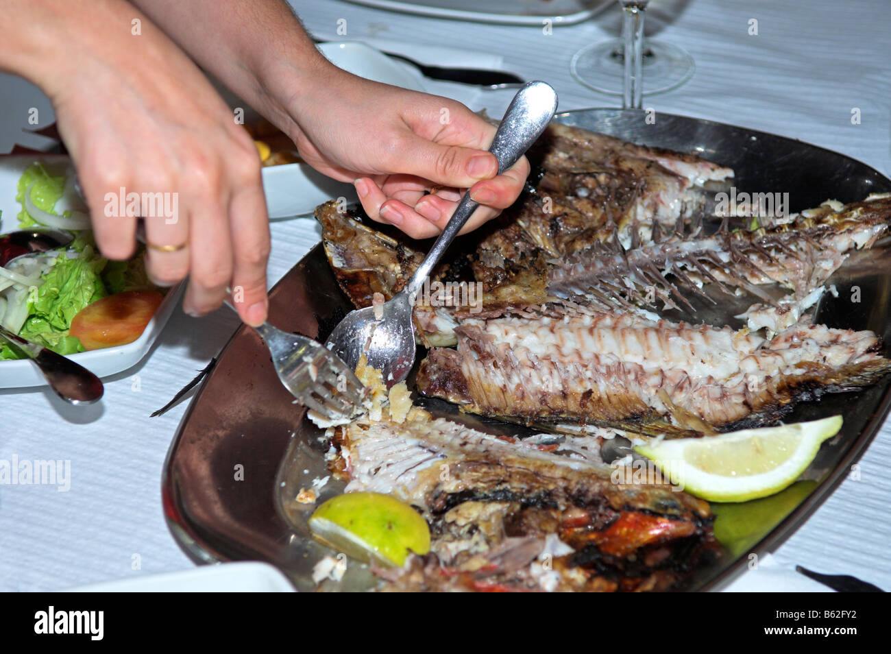 Waitress preparing fish to serve at restaurant table village of Maia ...