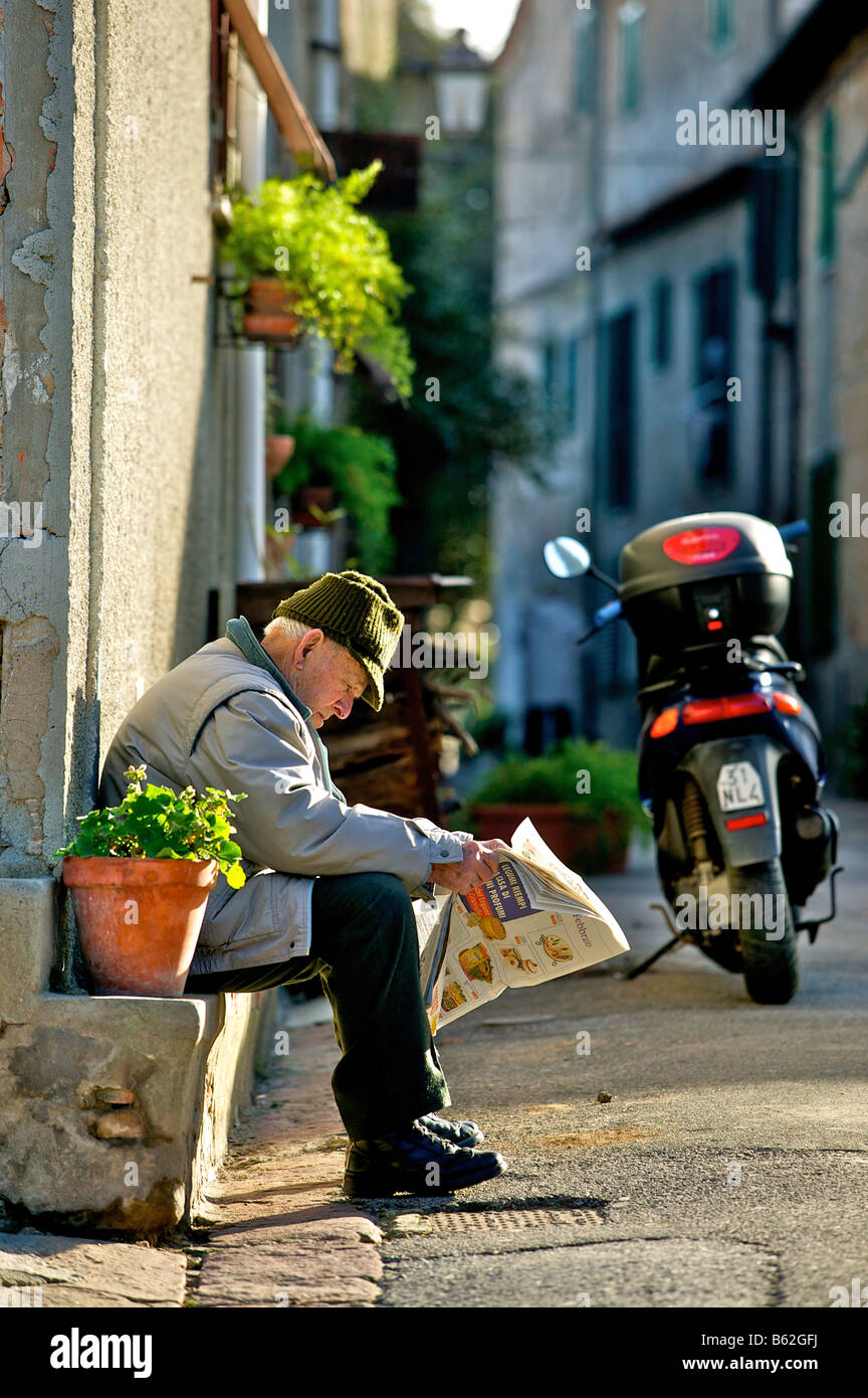 Old man reading newspaper in the village of Bolgheri Tuscany Italy ...