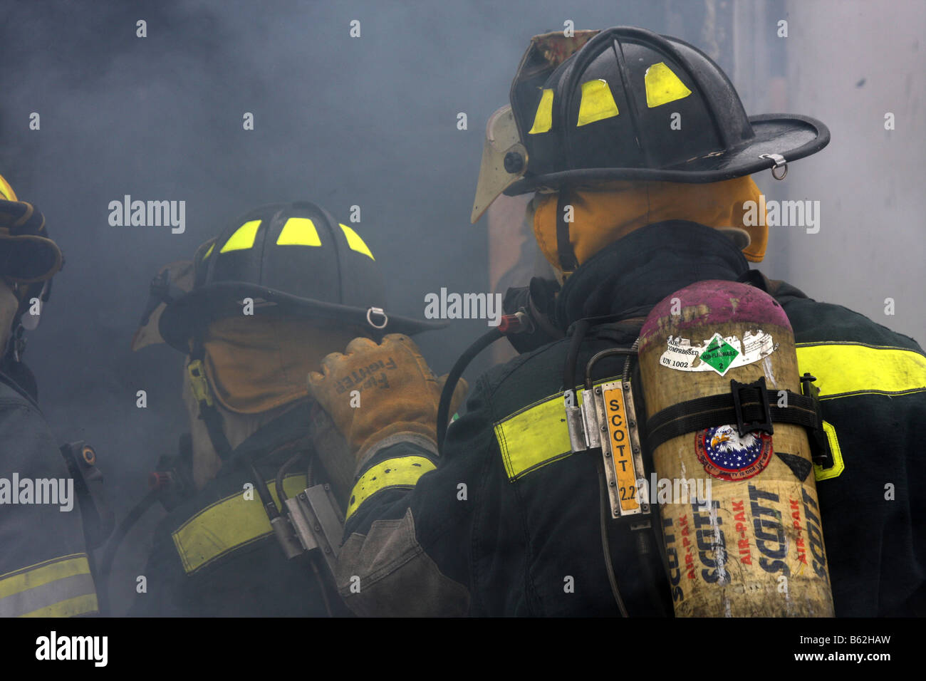 Three fire fighters surrounded by smoke while putting out a fire Stock ...