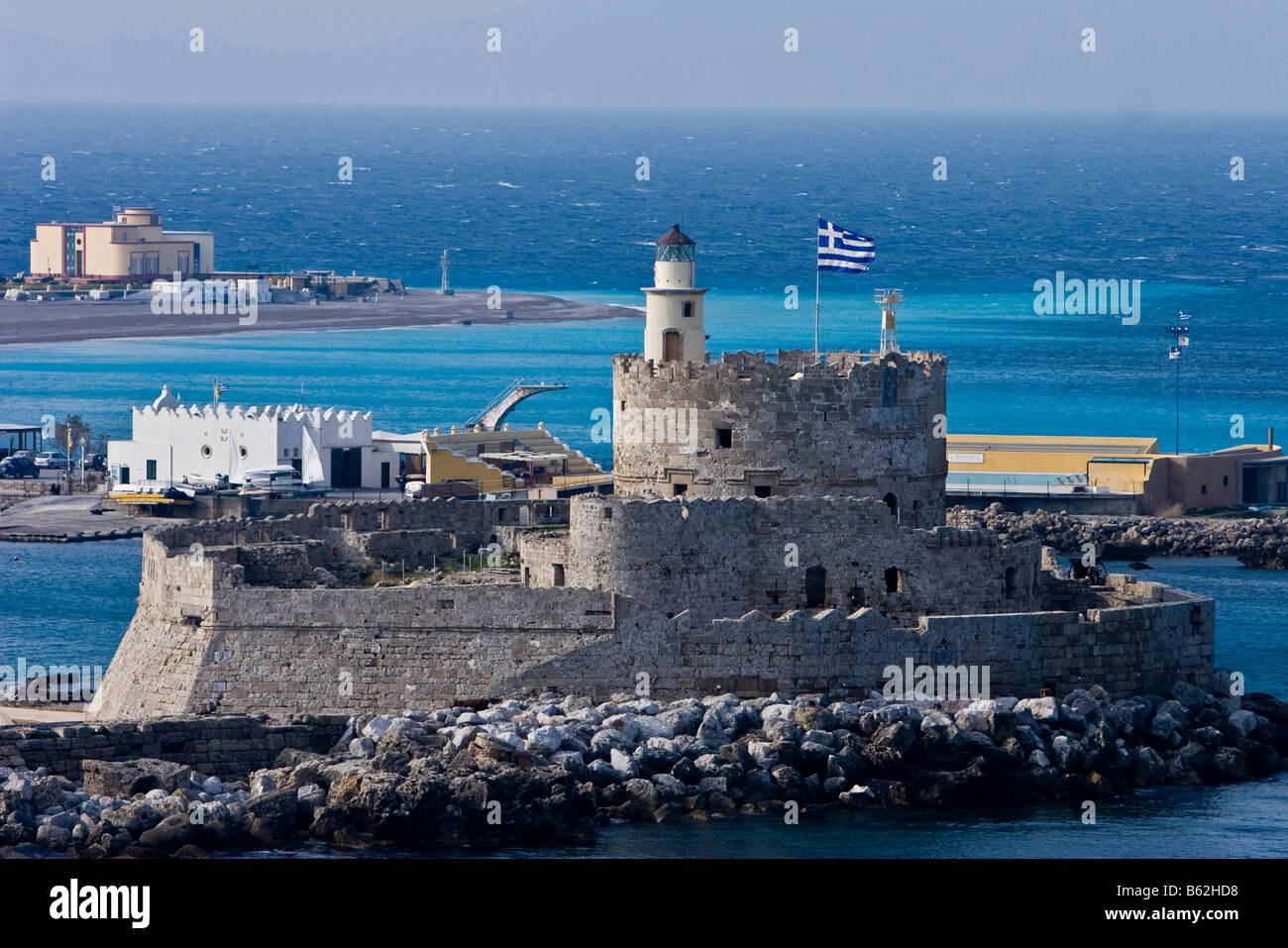 A Greek flags blows in the breeze near Rhodes City with a turqoise blue ...