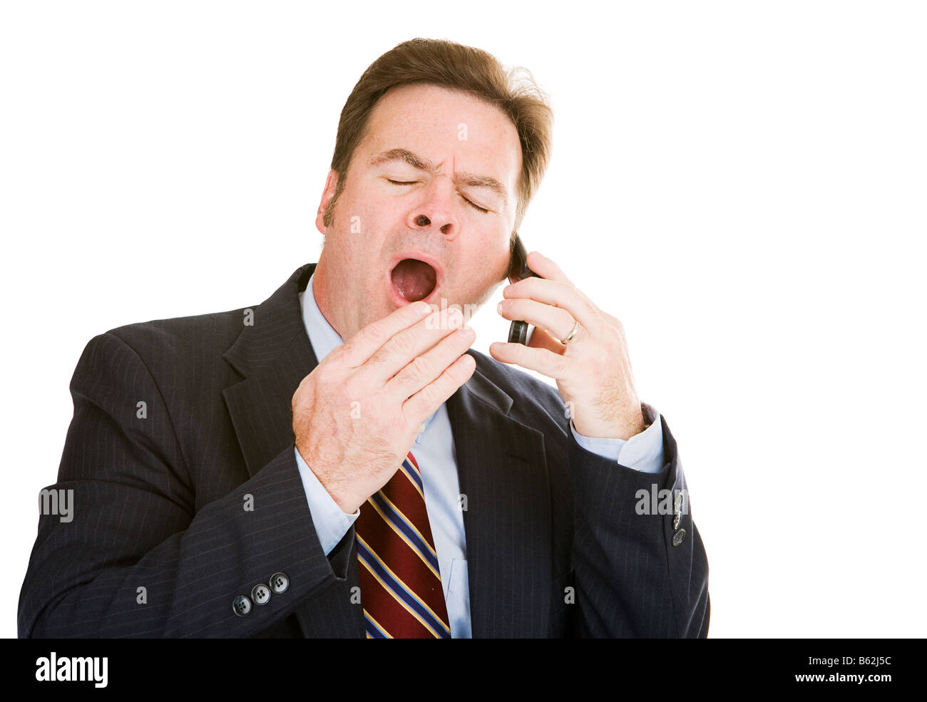 Businessman talking on his cellphone is yawning from boredom and ...