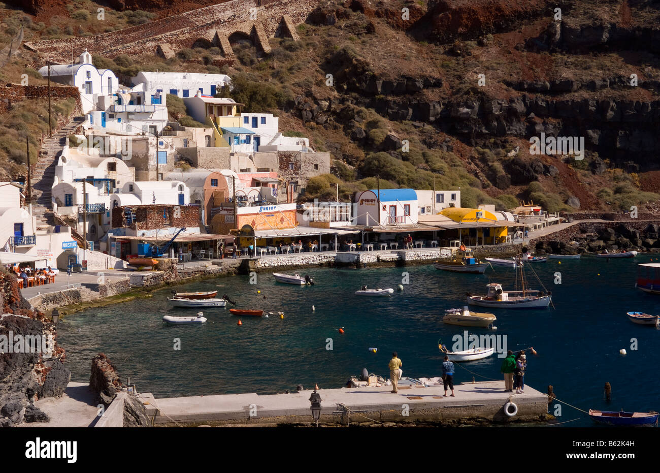 Beautiful traditional fishing village with boats at water below Oia n ...
