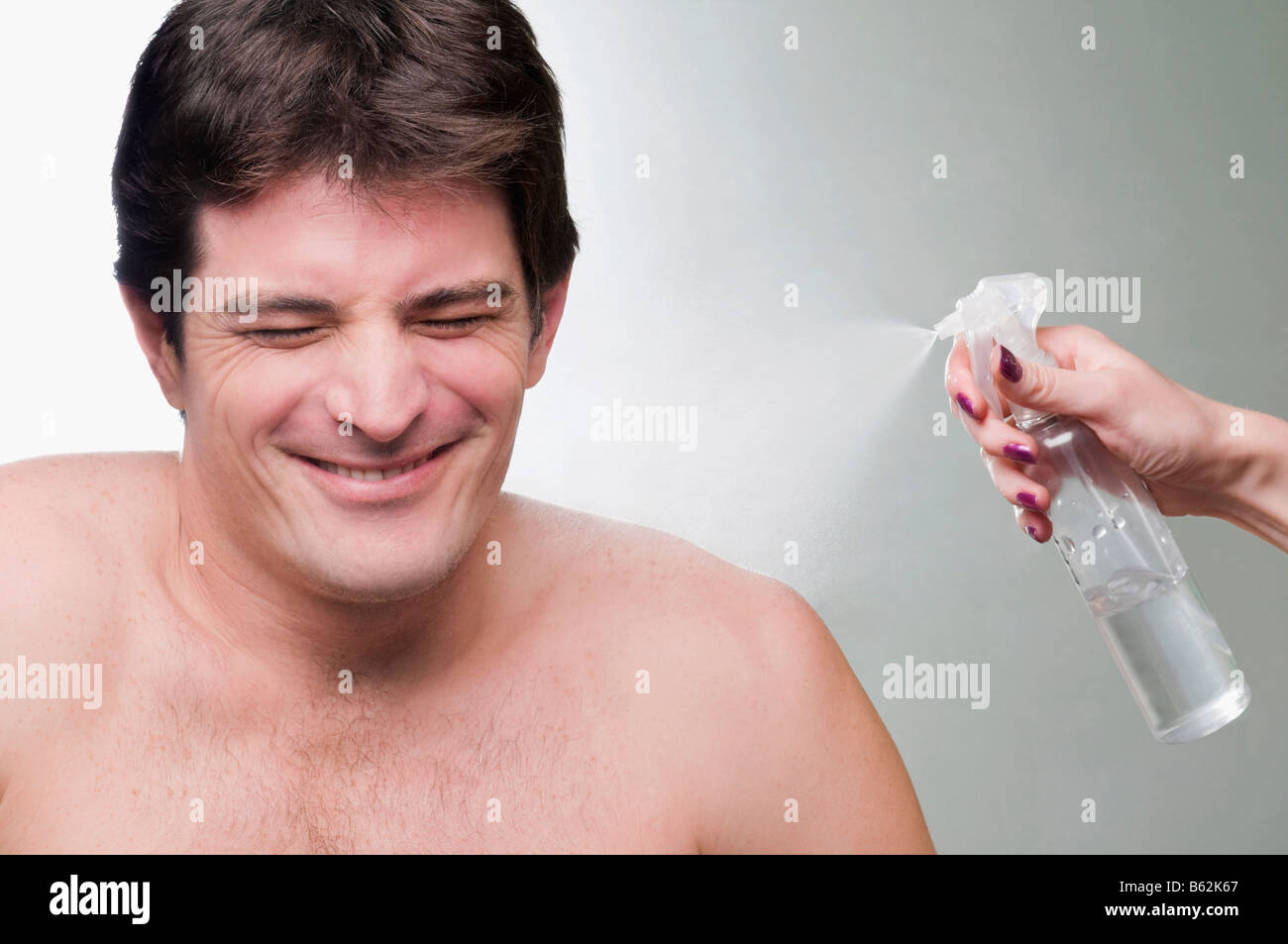 Close-up of a woman's hand spraying water on a mid adult man Stock ...