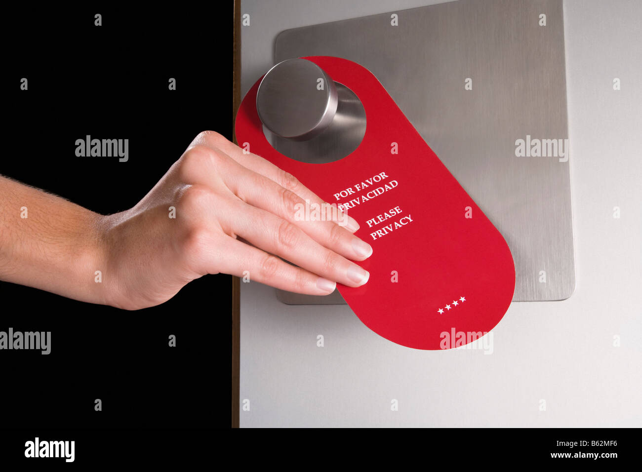 Close-up of a person's hand hanging do not disturb sign on a door ...